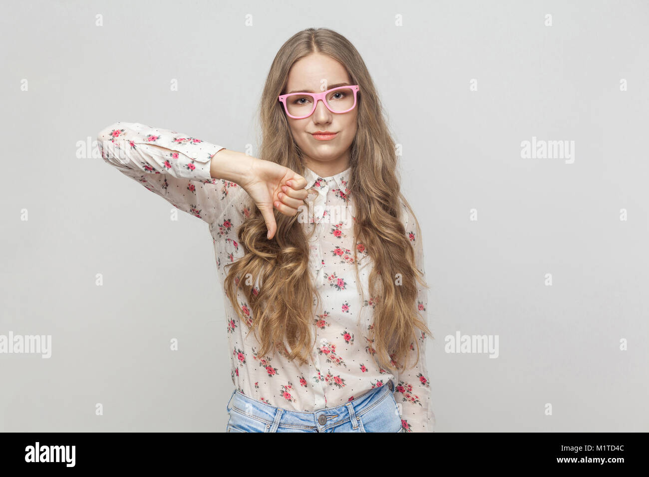 Dislike sign. Beautiful girl demonstrating dislike. Studio shot, gray ...