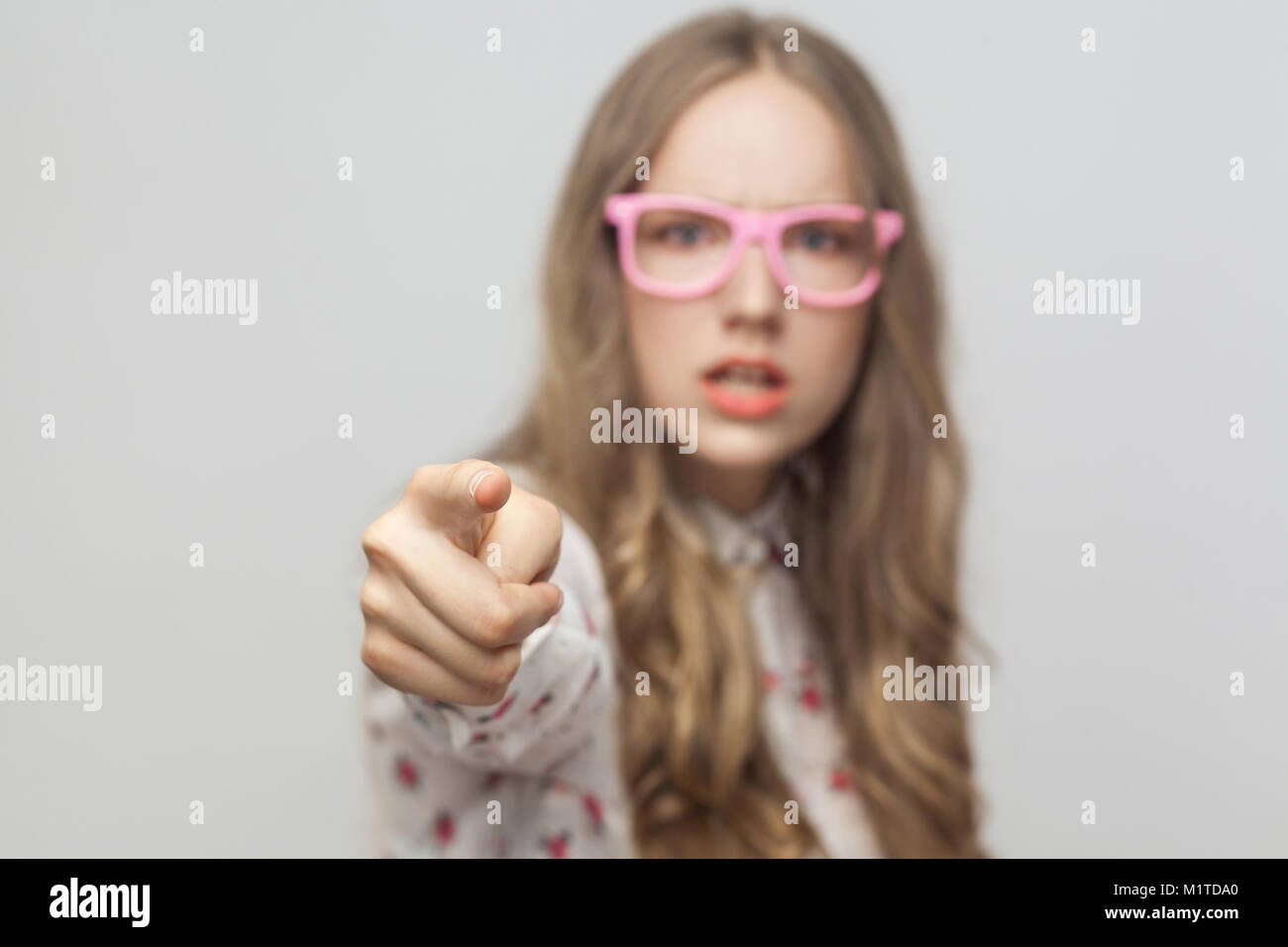 Hey you! Shocked young girl, pointing finger at camera and open mouth ...