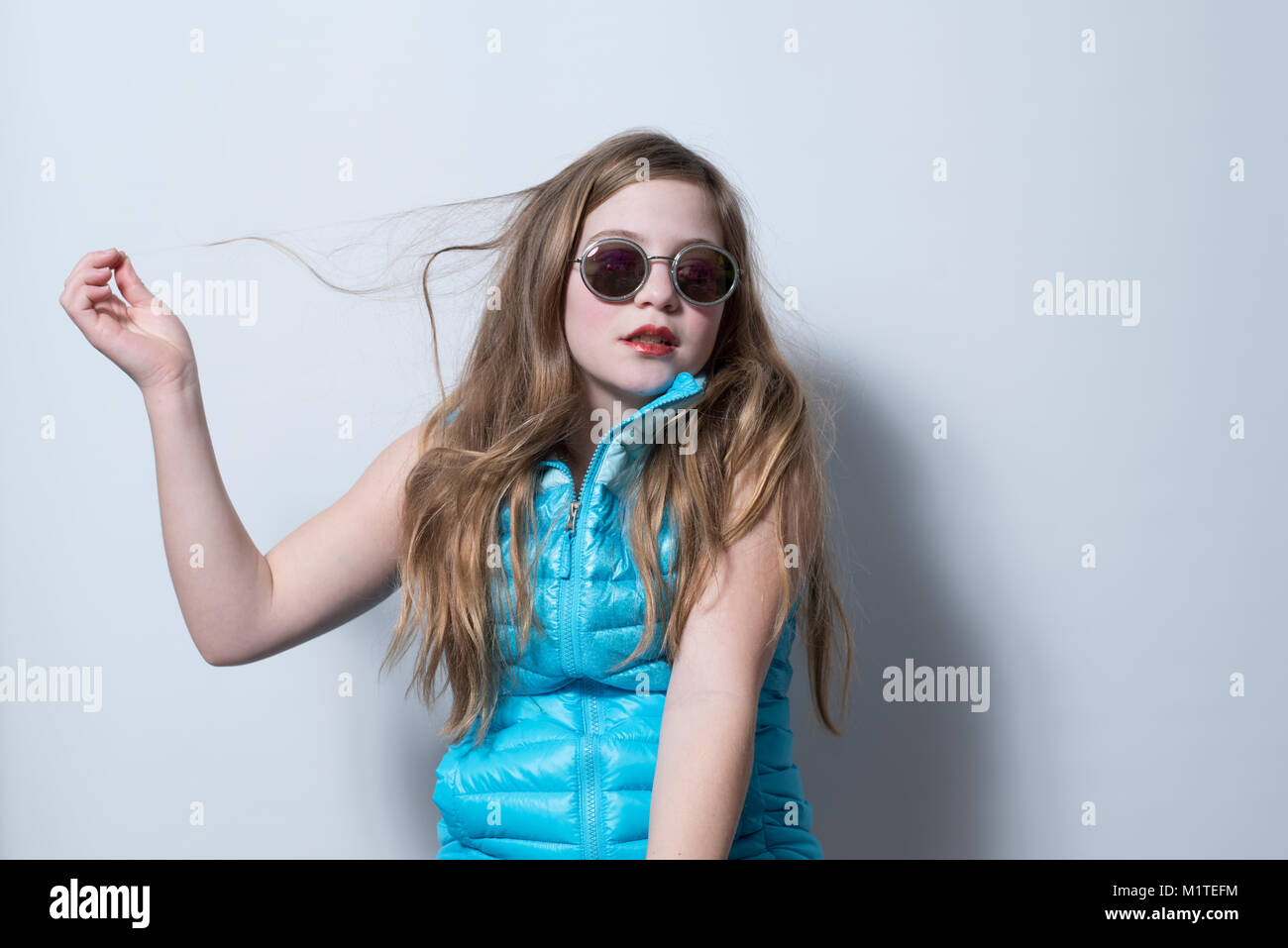 Girl in blue vest wearing round reflective sunglasses with indifferent ...