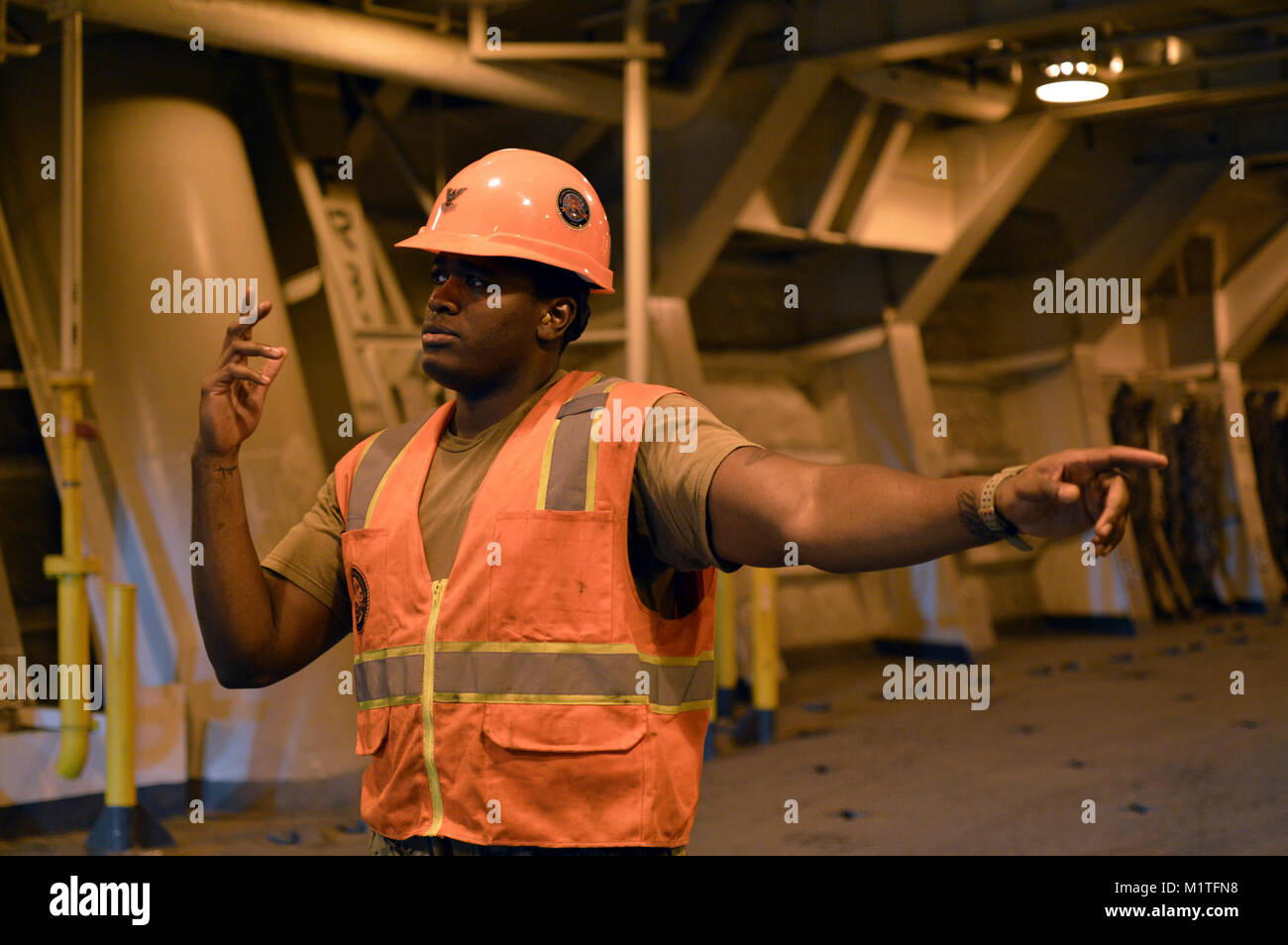 A Sailor assigned to a Navy Cargo Handling Battalion ground guides a ...