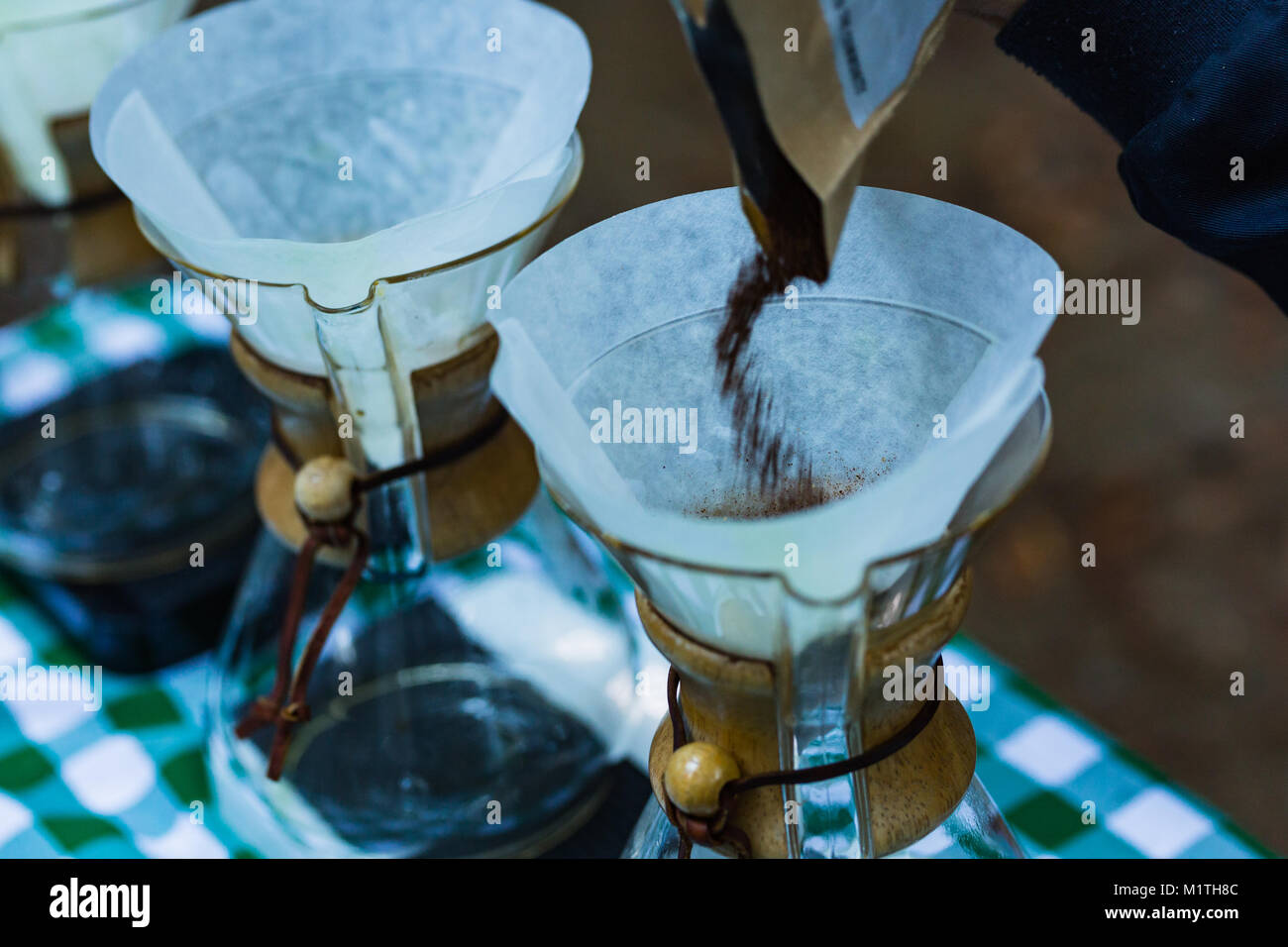 Barista pours ground coffee into paper filter in artisan glass brewer ...