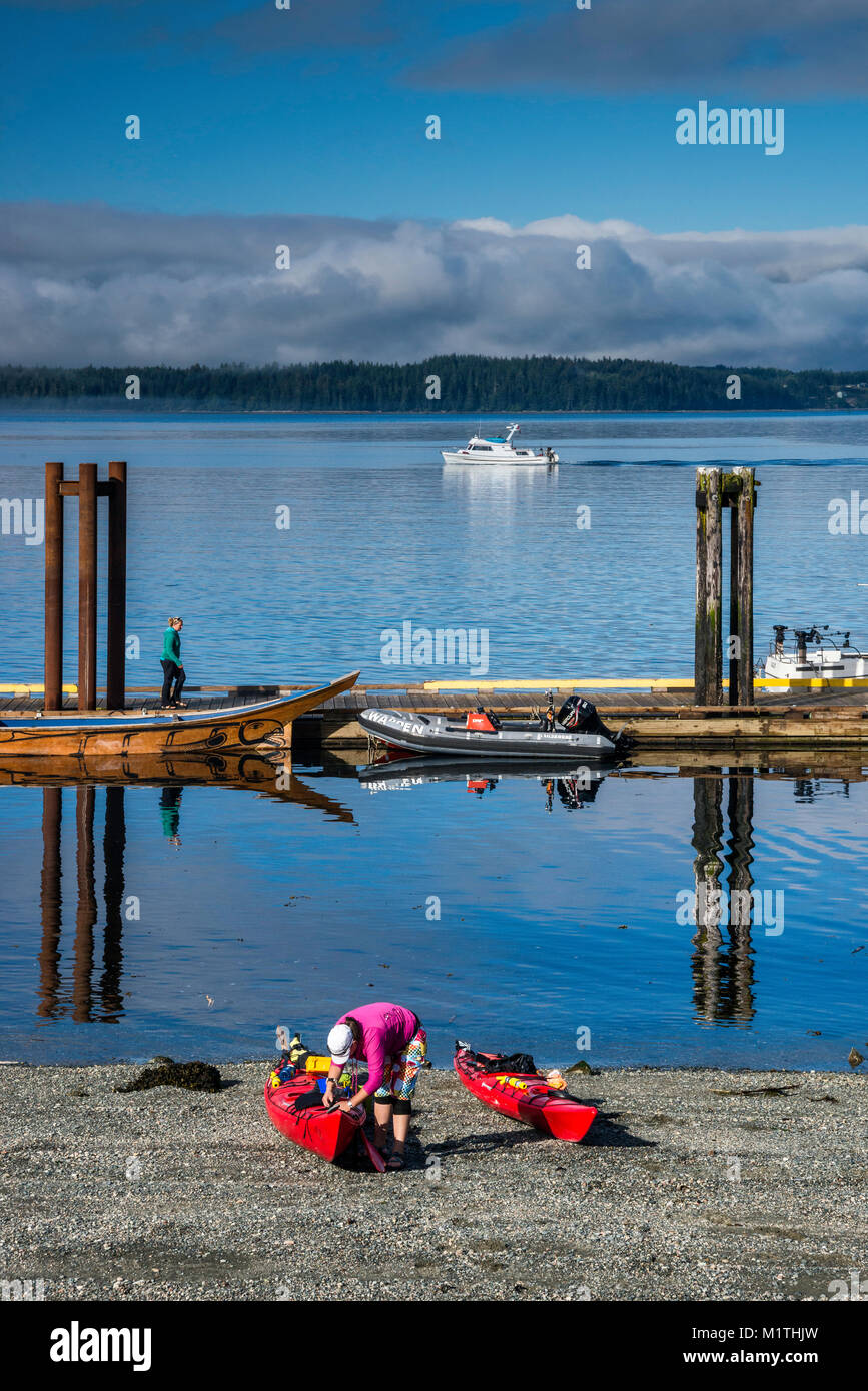 Woman preparing kayaks for a trip, small yacht in distance, Boat ...