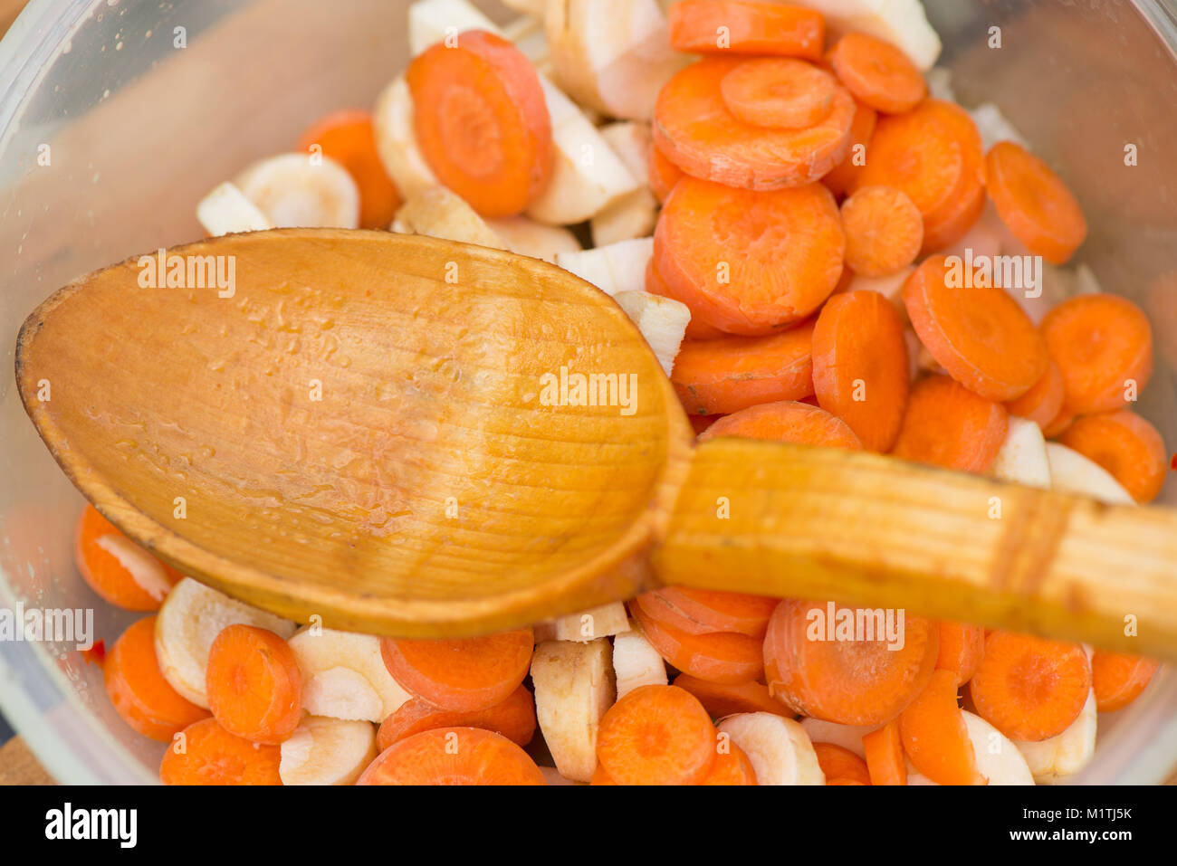Natural wooden spoon in a bowl full of chopped vegetables - slices of ...