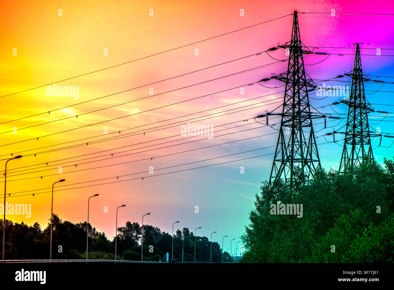 A silhouette of high voltage electrical tower structure next to highway ...