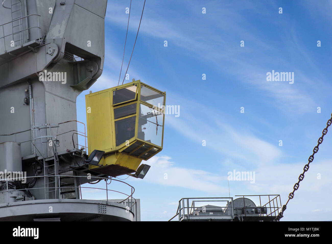 Shot of yellow control cabin with worker. Old, rusty, grey port crane ...