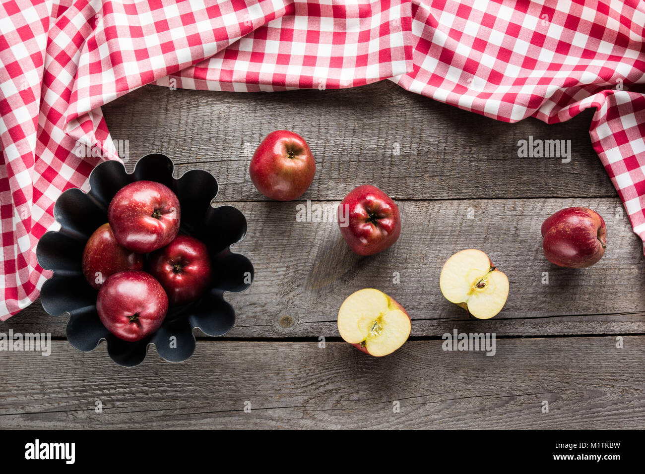 Ripe red apples in baking form on wooden board with red checkered ...