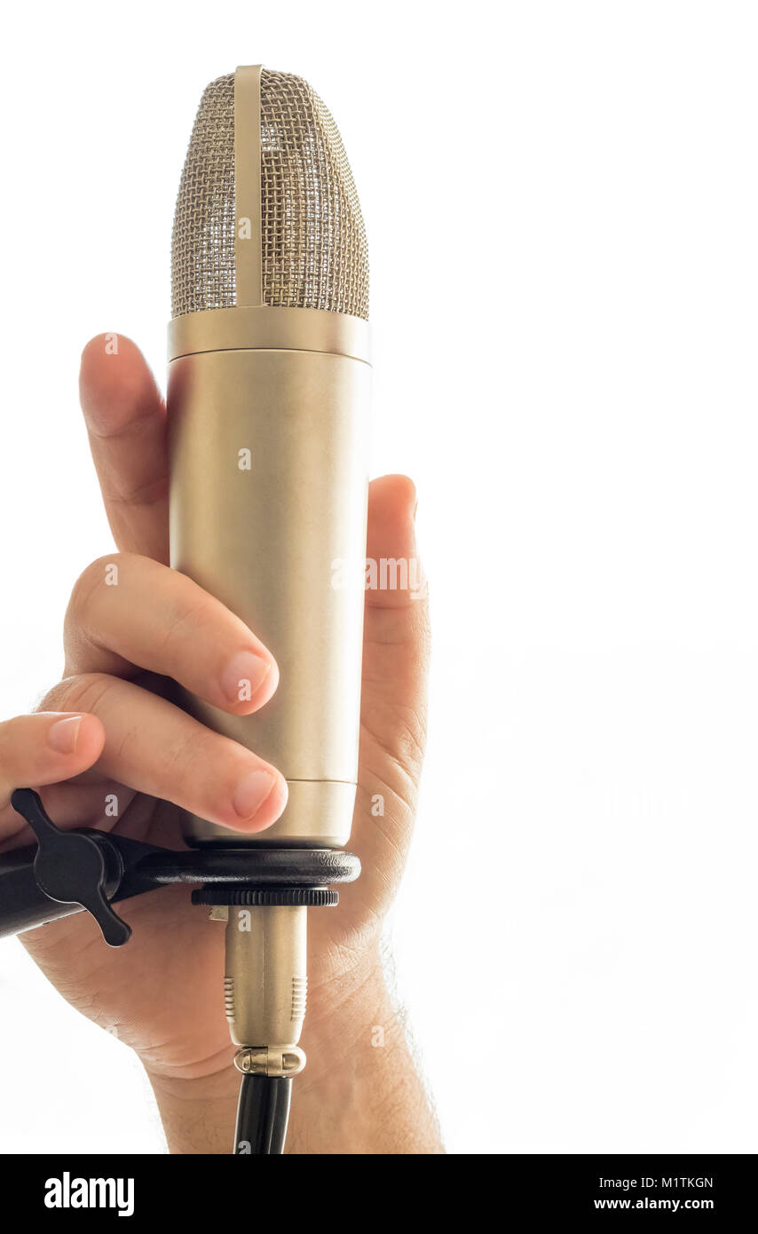 A microphone is on a mic stand. A hand man's hand is holding onto the ...
