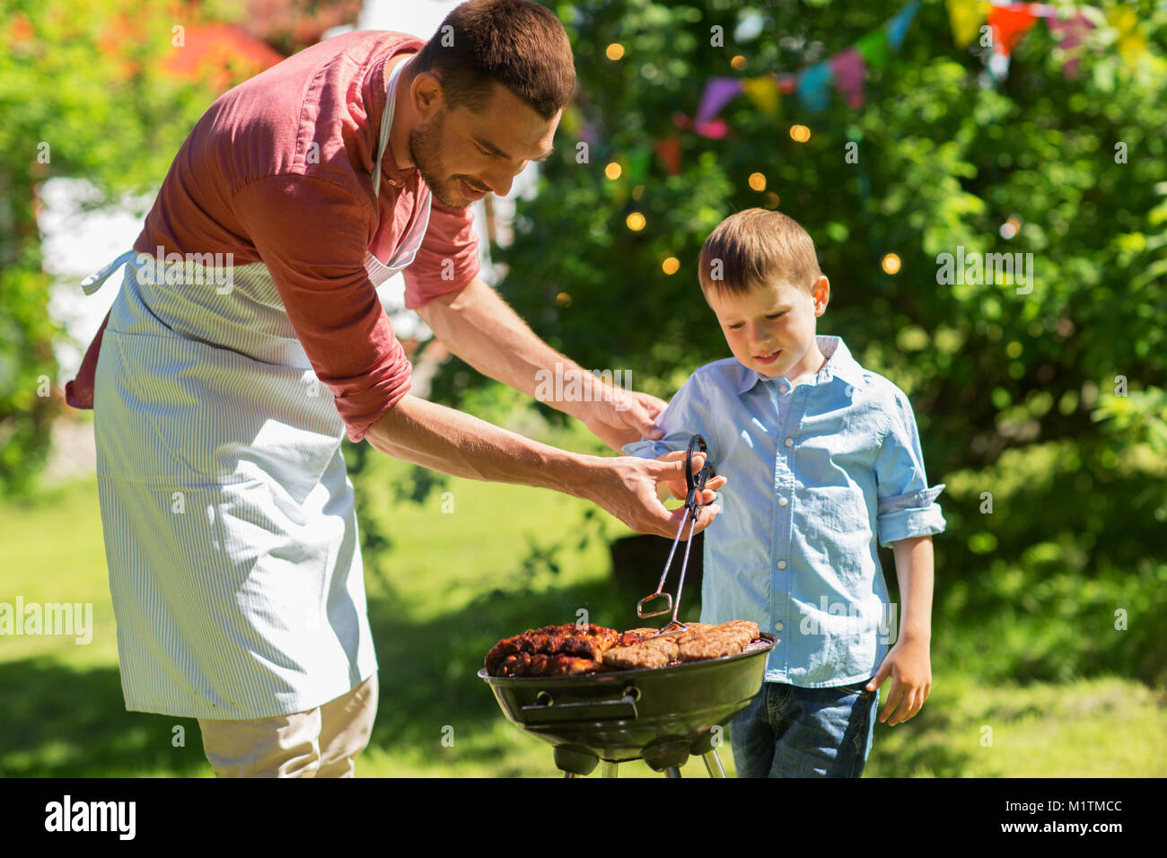 father and son cooking meat on barbecue grill Stock Photo - Alamy