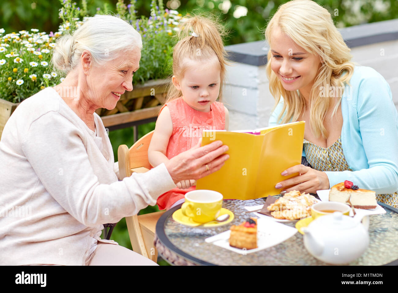 happy family reading book at cafe Stock Photo - Alamy