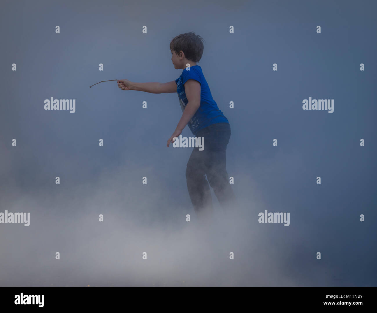Boy in blue playing with stick in thick fog Stock Photo - Alamy