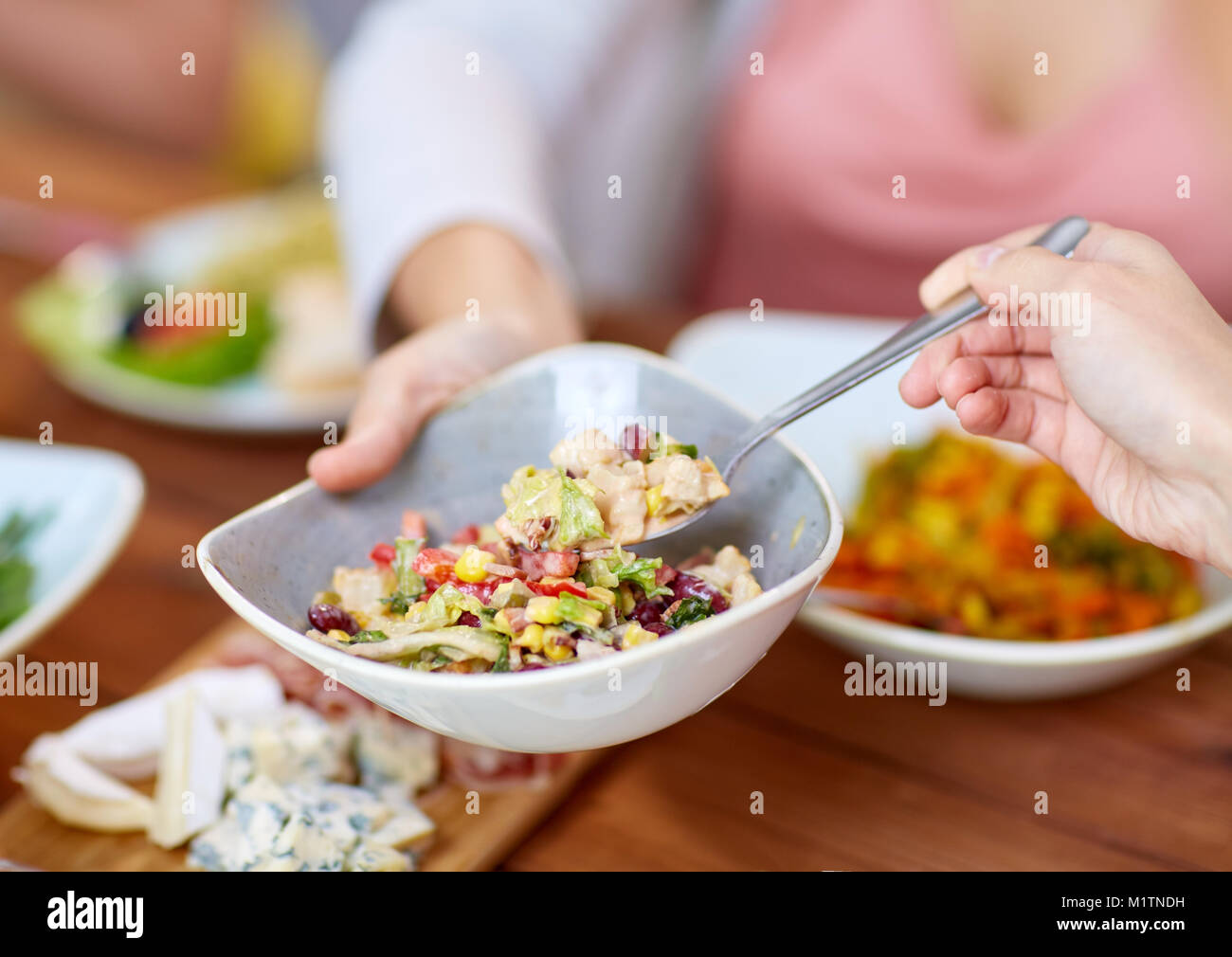 people eating salad at table with food Stock Photo - Alamy