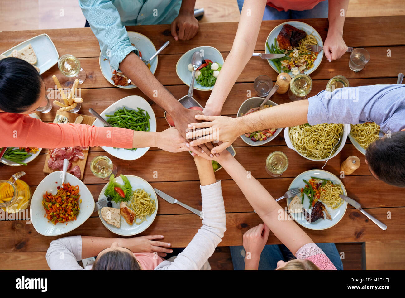 people holding hands together over table with food Stock Photo - Alamy