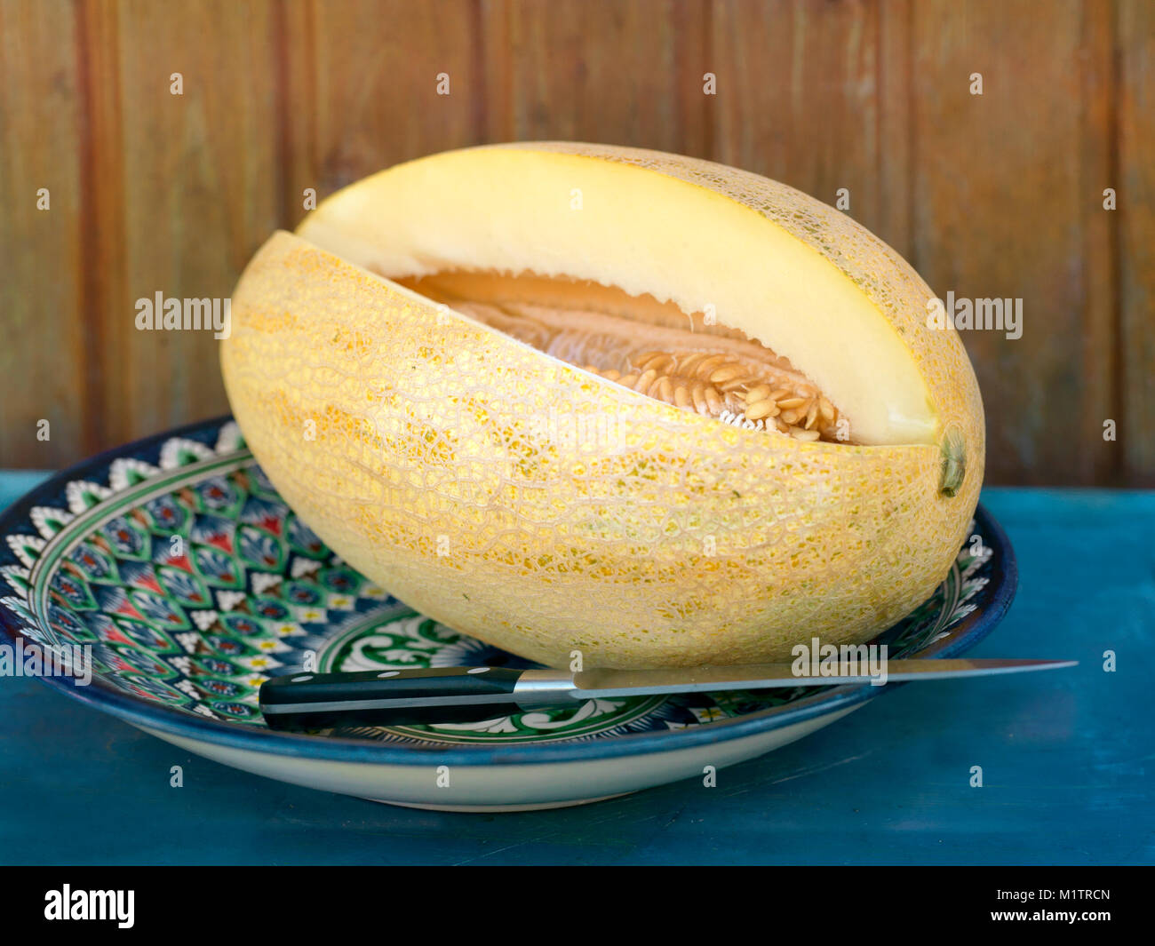 Sweet and juicy sliced melon laid on a colorful plate and knife ...