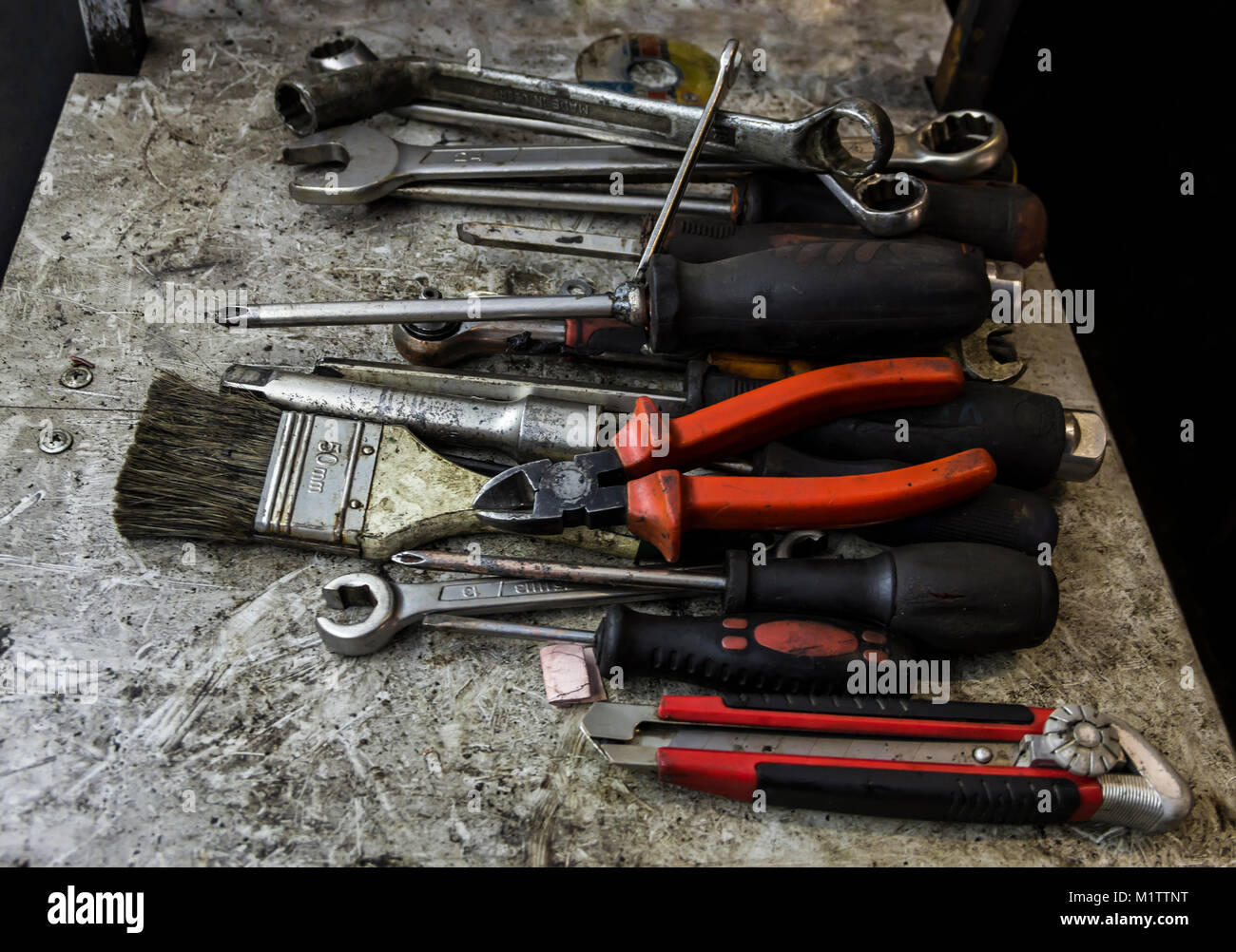 An untidy workbench full of greasy old tools set for repairing or ...