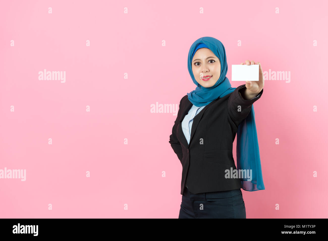 smiling young muslim female agent showing white empty business card ...