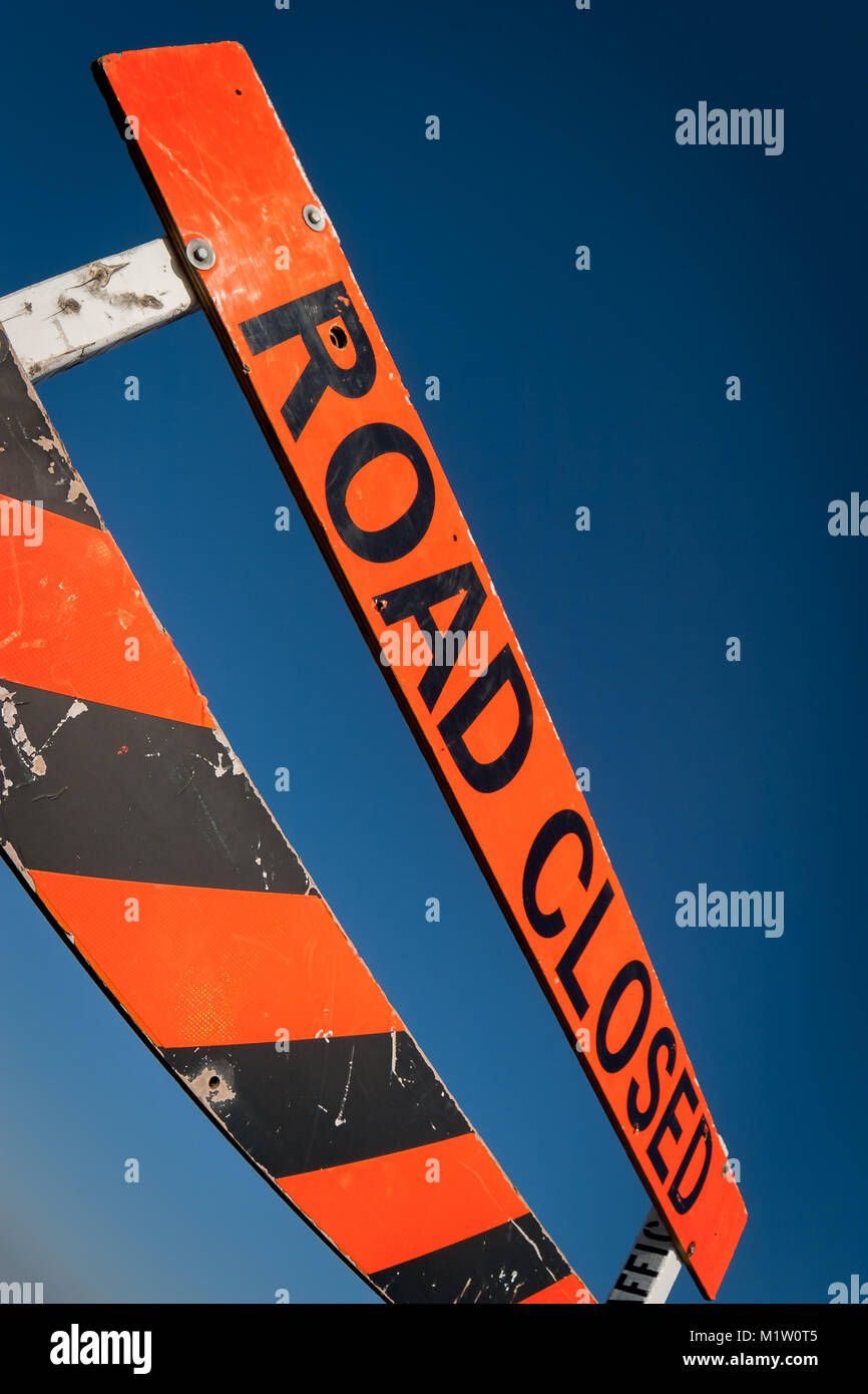 A Road Closed construction sign against a clear blue sky background ...