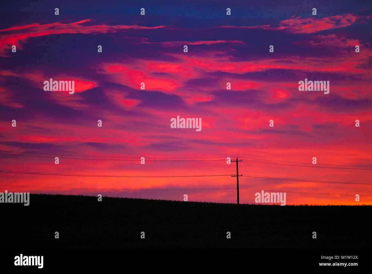 Colorful sky at sunrise with silhouetted power or telephone poles and ...
