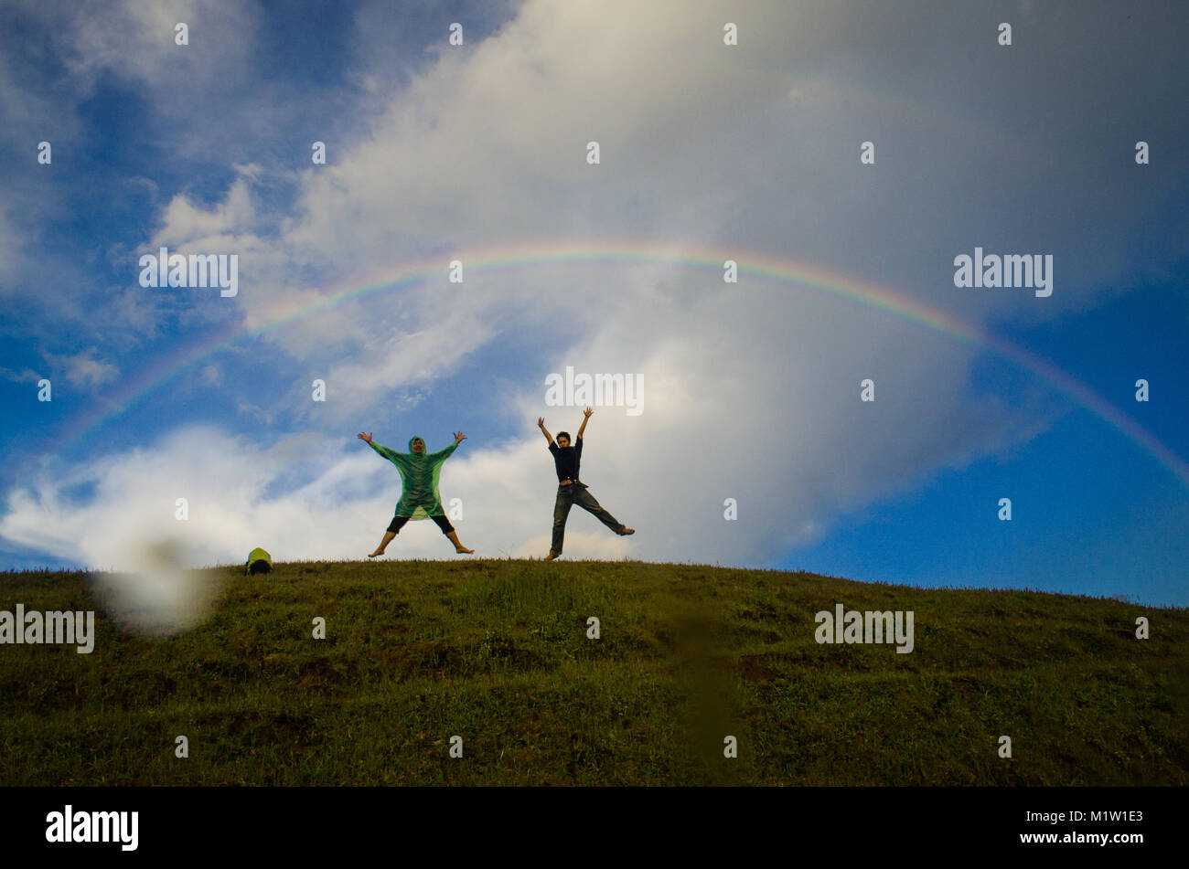group of happy friends stands on sunset backdrop with raised arms ...