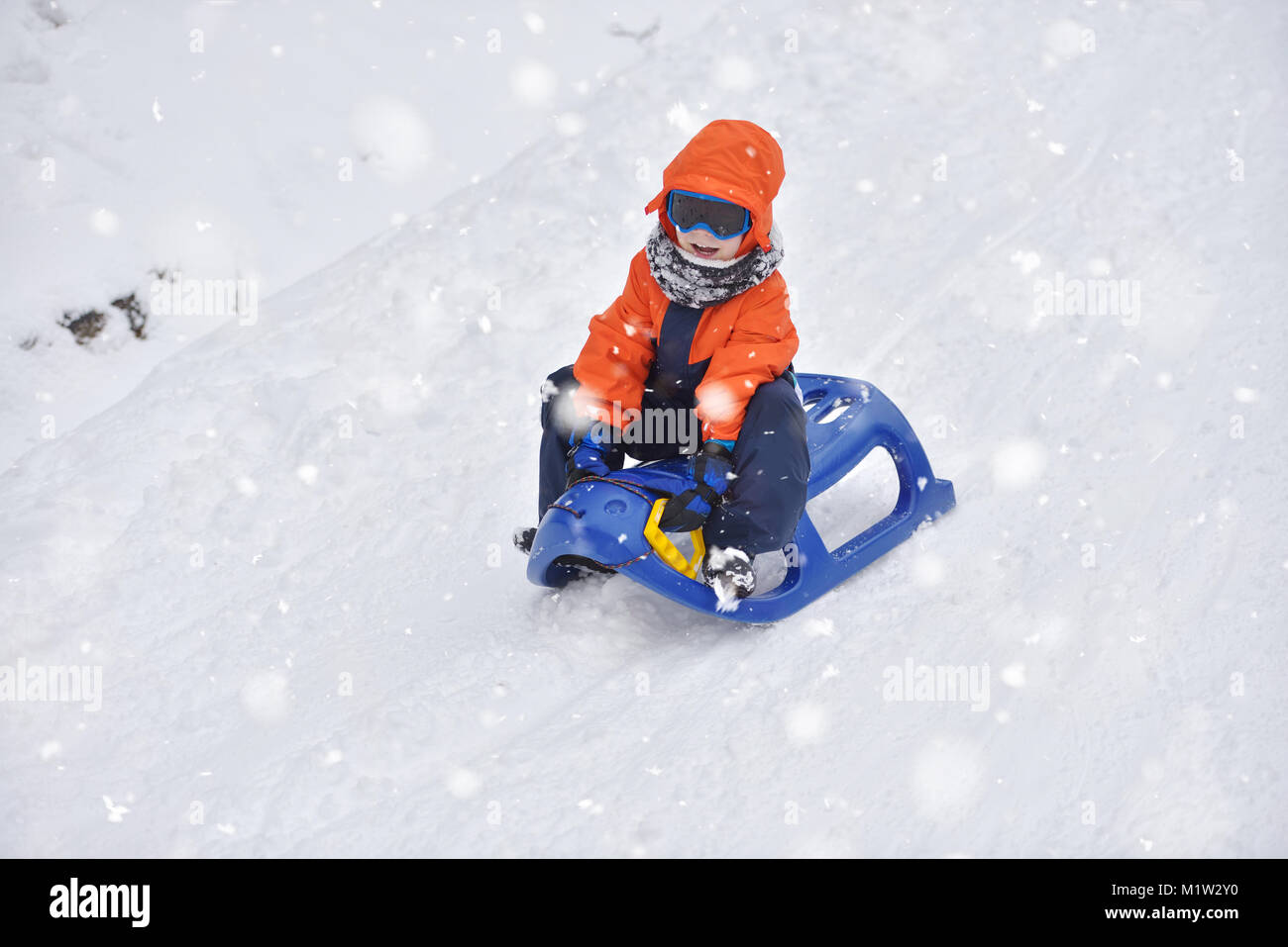 Little boy riding on snow slides in winter time Stock Photo - Alamy