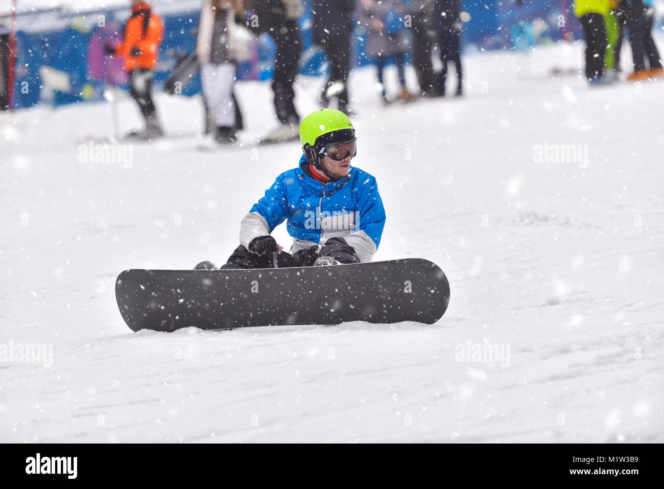 Young man on snowboard downhill with people in the background Stock ...