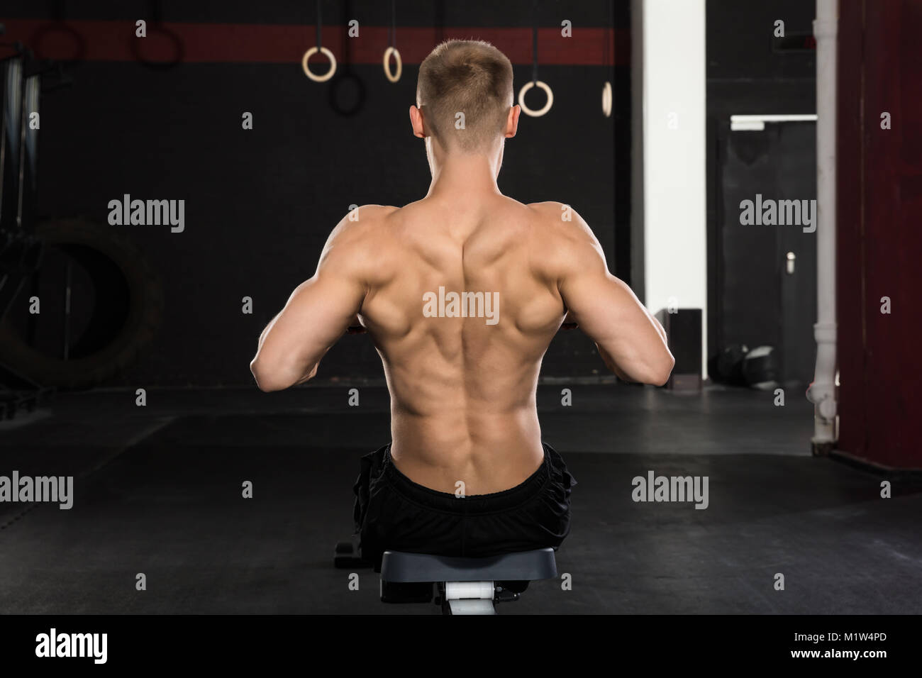 Rear View Of A Young Athlete Man Working Out On Row Machine In Gym ...