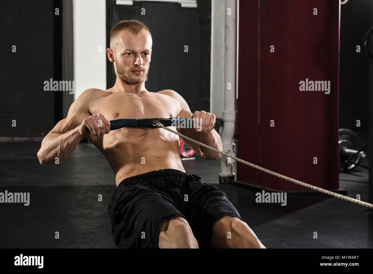 Portrait Of A Young Athlete Man Using Rowing Machine In The Gym Stock ...
