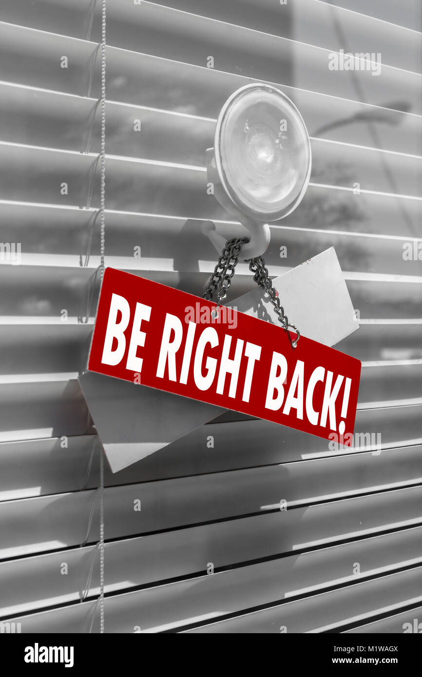 A sign saying "be right back" on a glass door with a white, closed ...