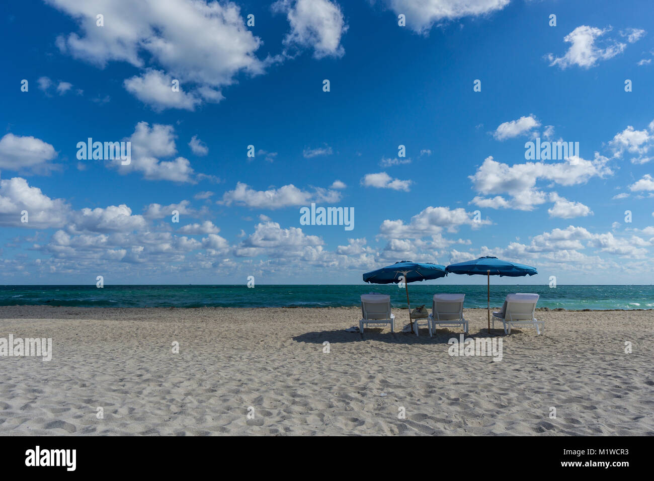 USA, Florida, Empty miami beach with two blue sunshades and three deck ...