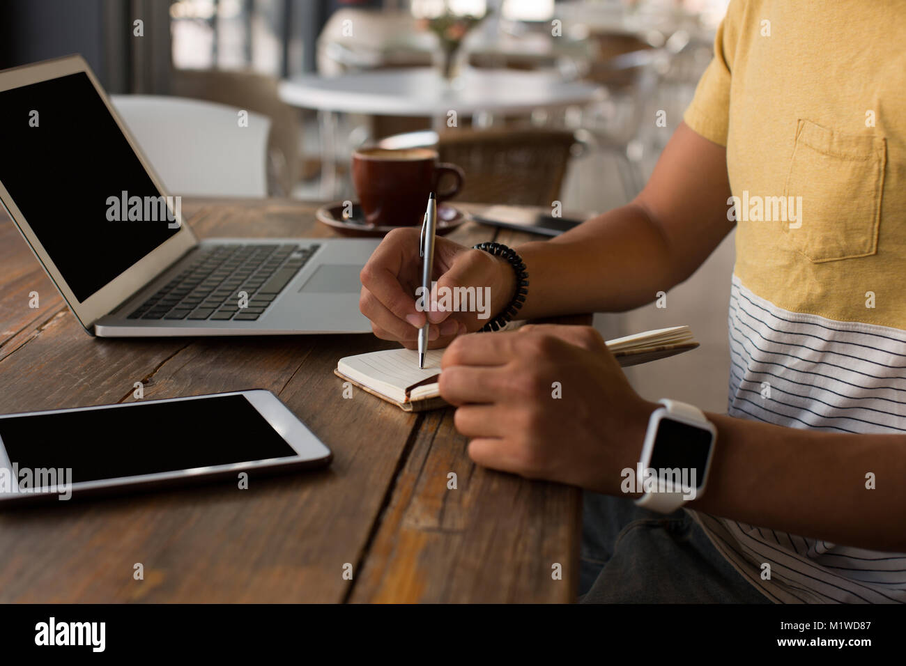 Man writing on a diary in caferetia Stock Photo - Alamy