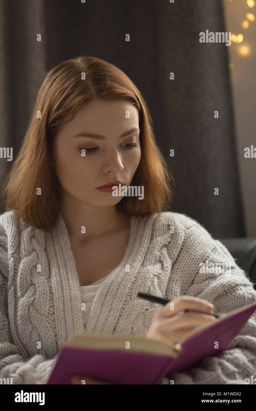 Woman writing on a diary in living room Stock Photo - Alamy