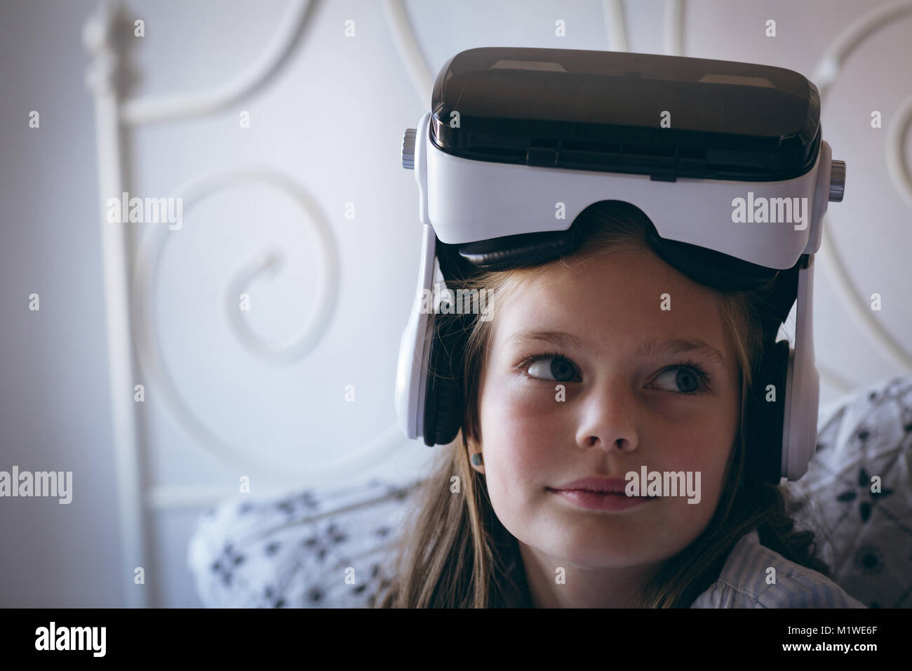 Girl with virtual reality headset sitting on bed Stock Photo - Alamy