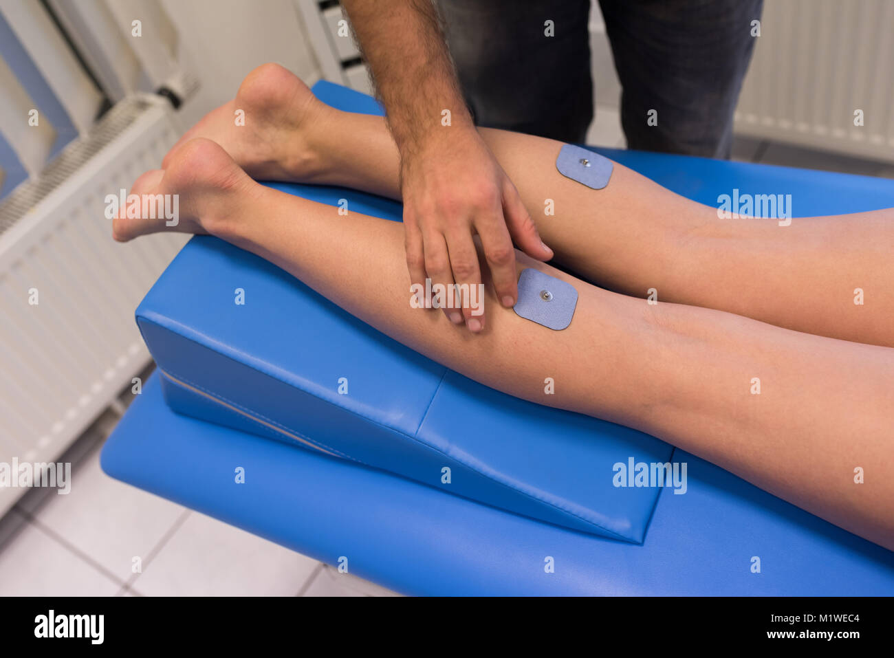 Physiotherapist placing pads on woman legs Stock Photo - Alamy