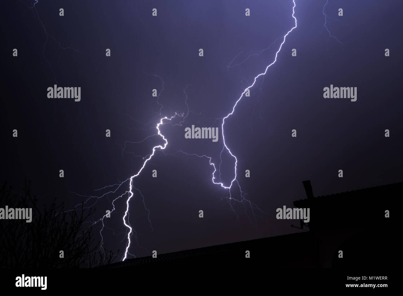 Cloud to ground electric lightning behind house roof top Stock Photo ...
