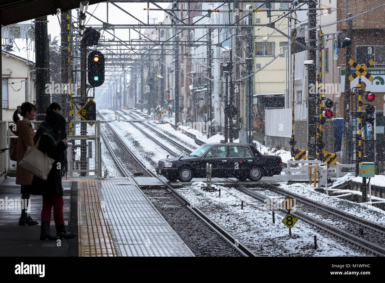 Tokyo, Japan. 2nd Feb, 2018. A taxi is seen crossing the train tracks ...