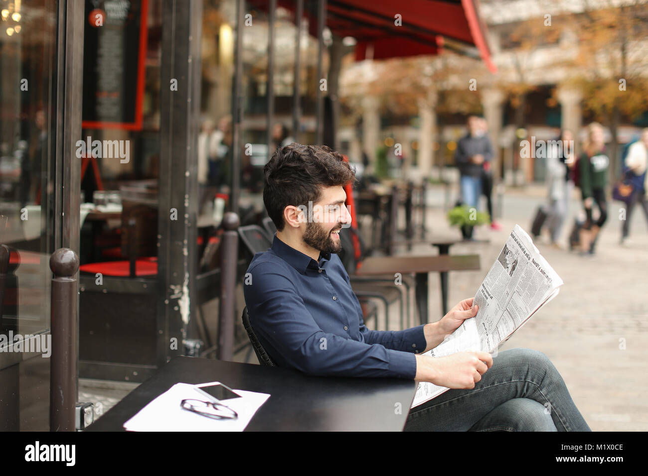 Journalist with close up face reading newspaper article at cafe Stock ...