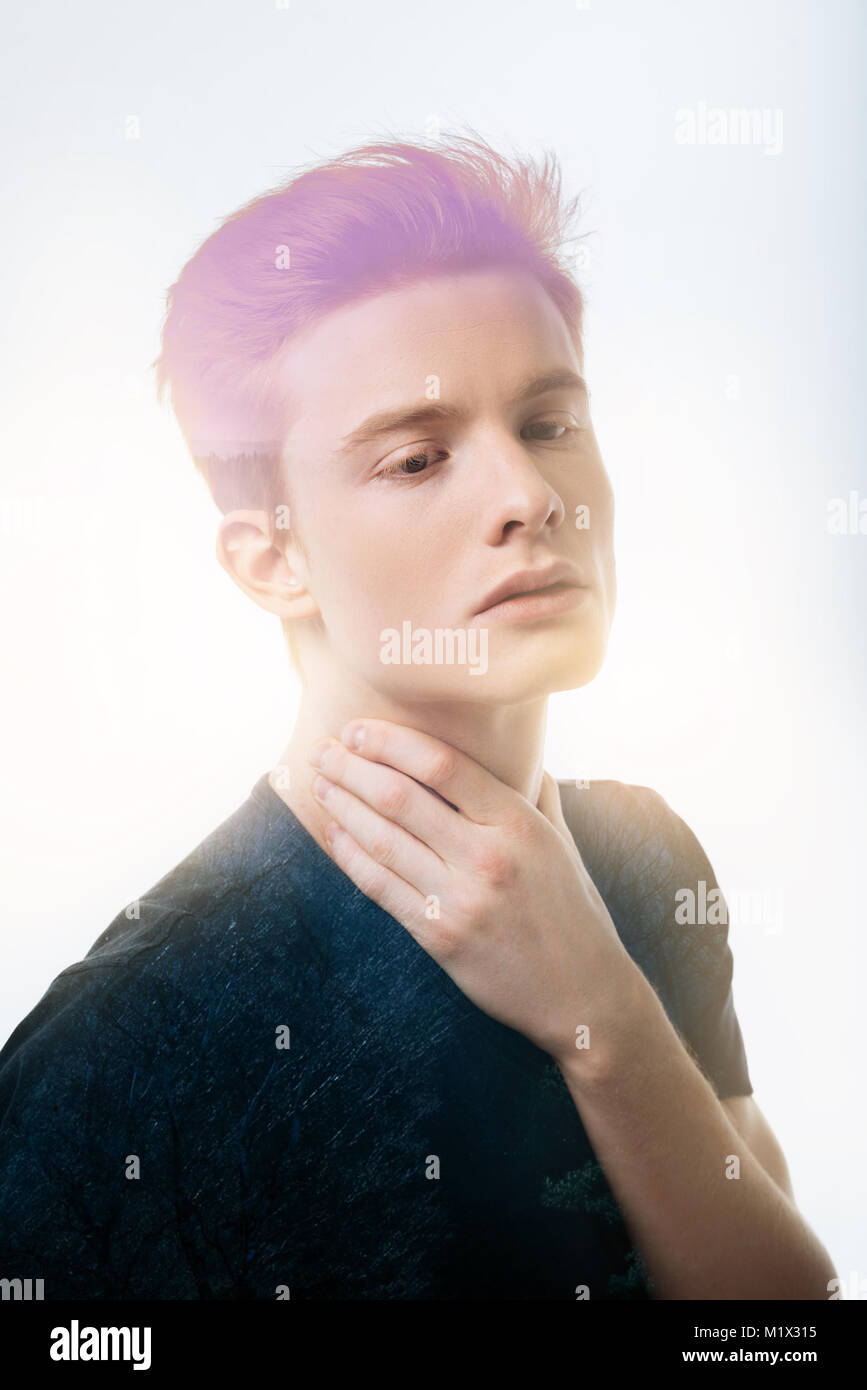 Thoughtful handsome boy touching to his neck and looking down Stock ...