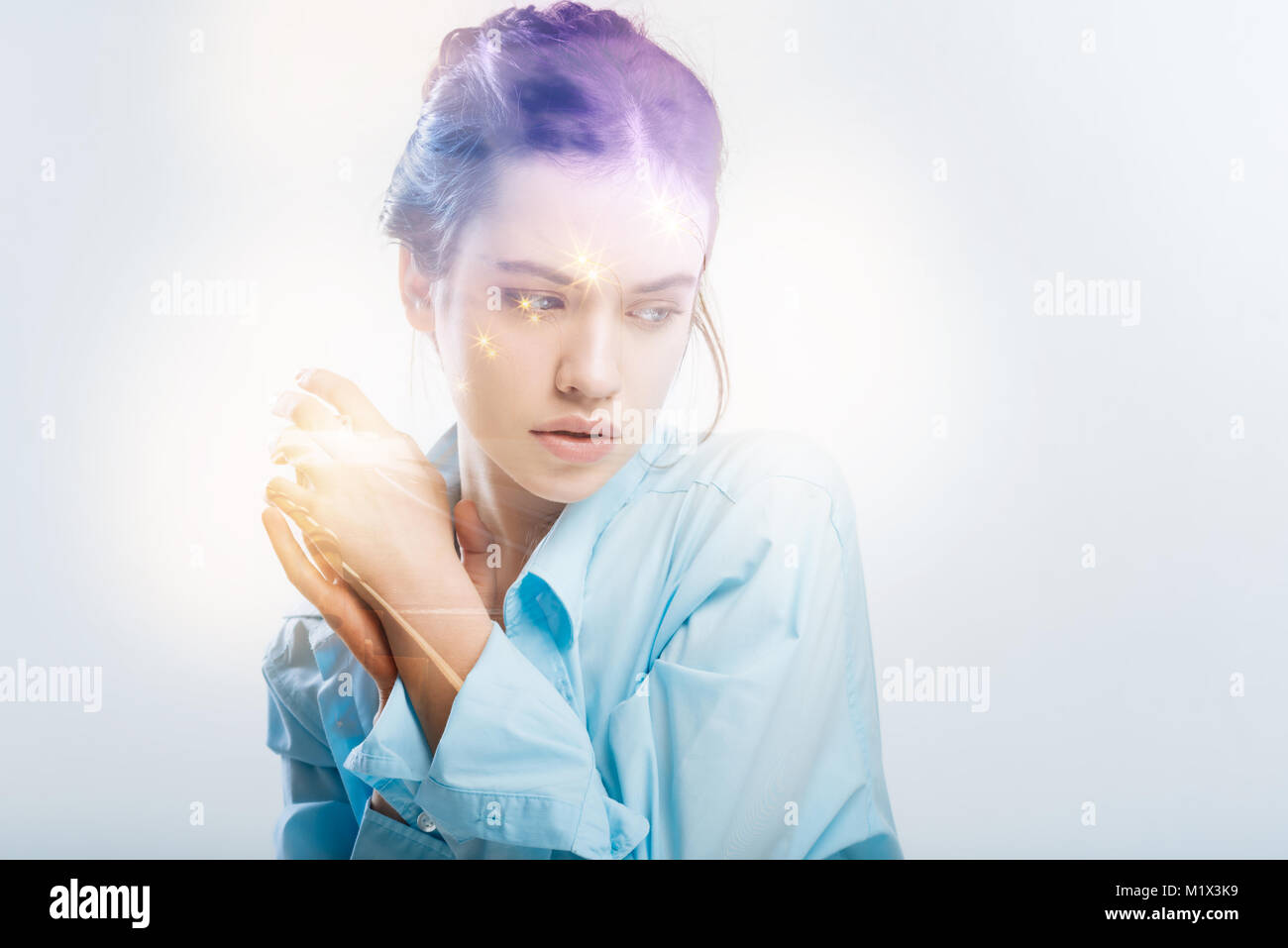 Concentrated thoughtful woman holding hands near neck looking down ...