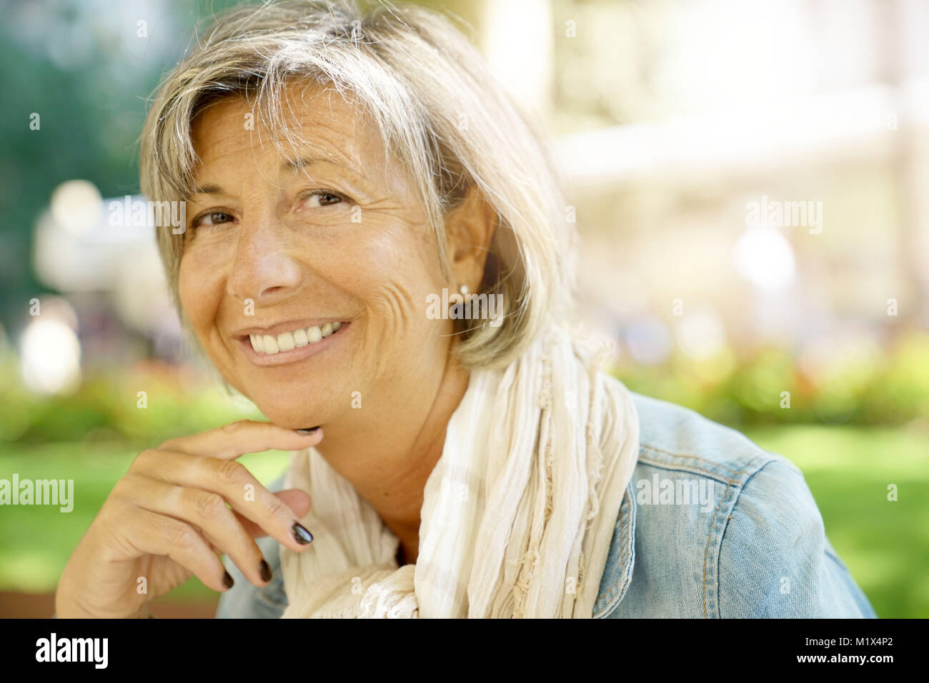 Portrait of smiling senior woman sitting on bench Stock Photo - Alamy