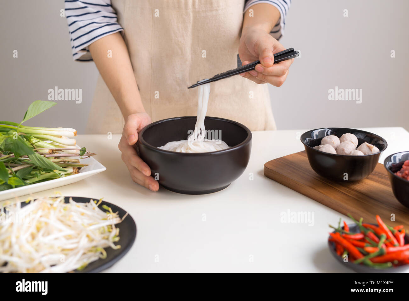 Female chef prepare traditional Vietnamese soup Pho bo with herbs, meat ...