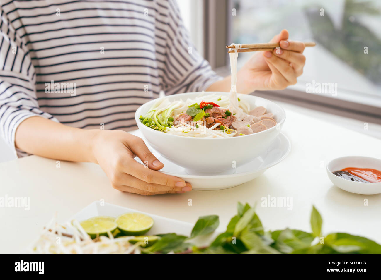 Woman eating traditional Vietnamese Pho noodle using chopsticks Stock ...