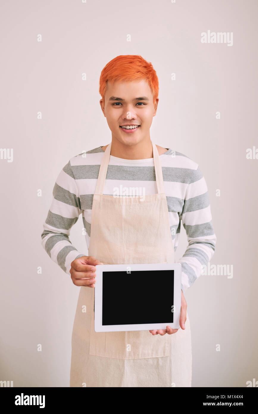 Happy and confident male cafe worker in apron smiling at a camera ...
