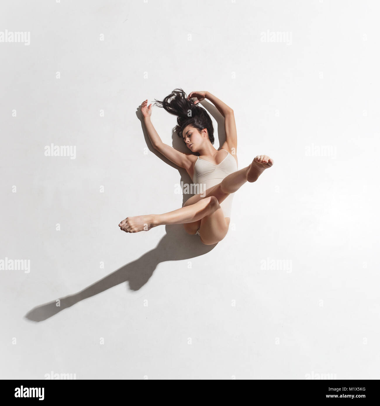 Young beautiful dancer in beige dress dancing on gray background Stock ...