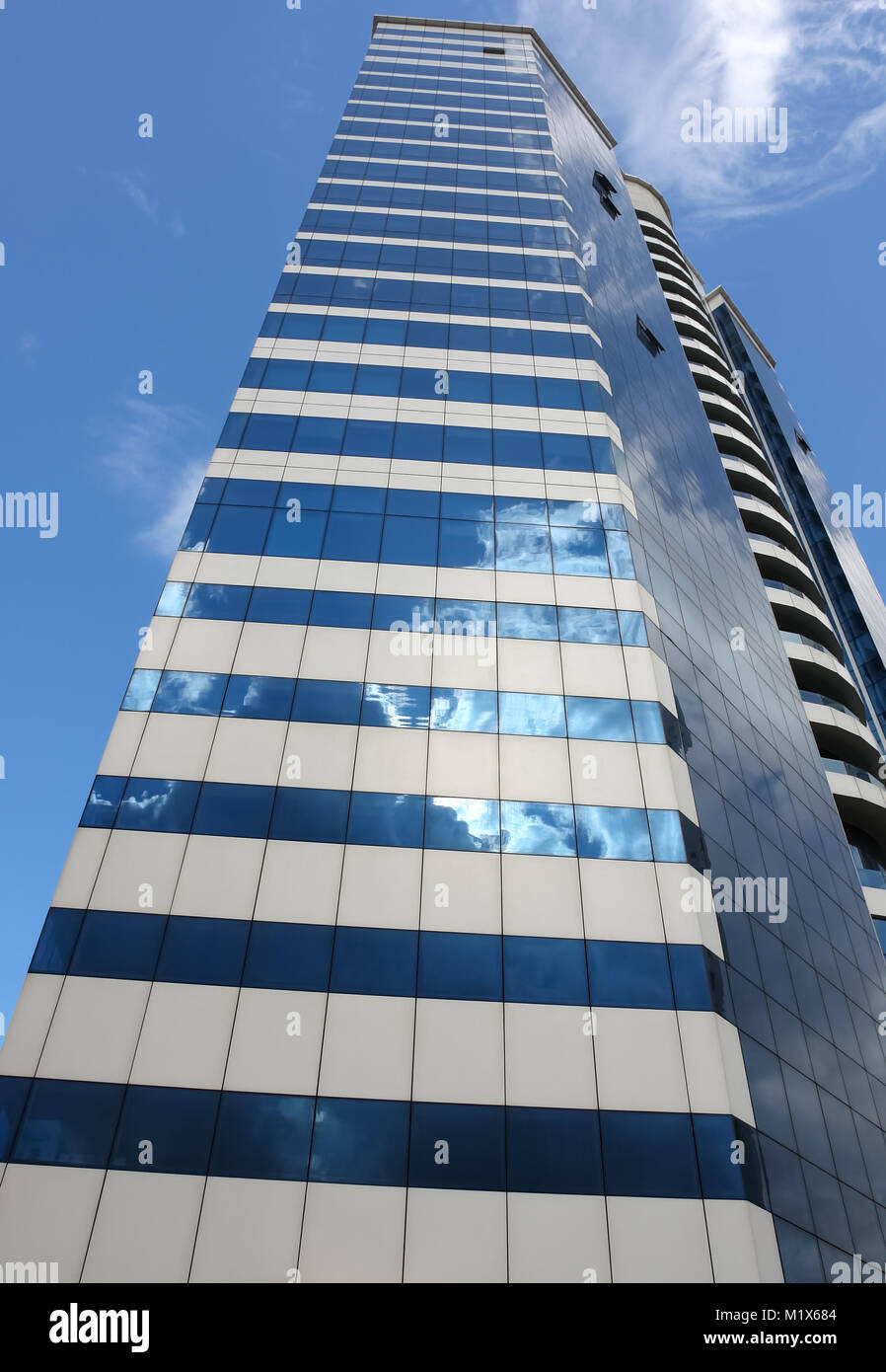 Mirror reflection of the blue sky and white clouds in a modern high ...