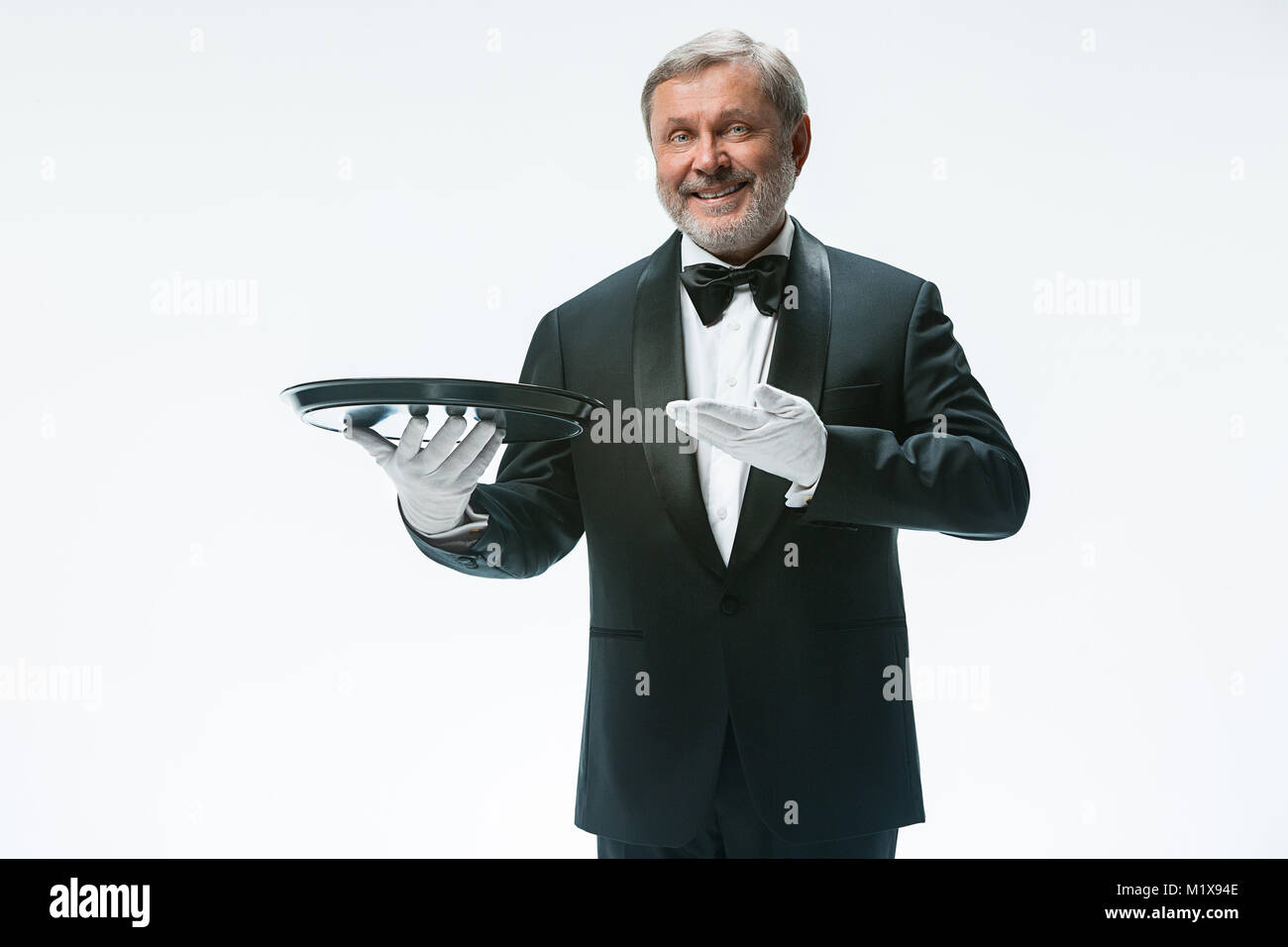 Senior waiter holding tray Stock Photo - Alamy