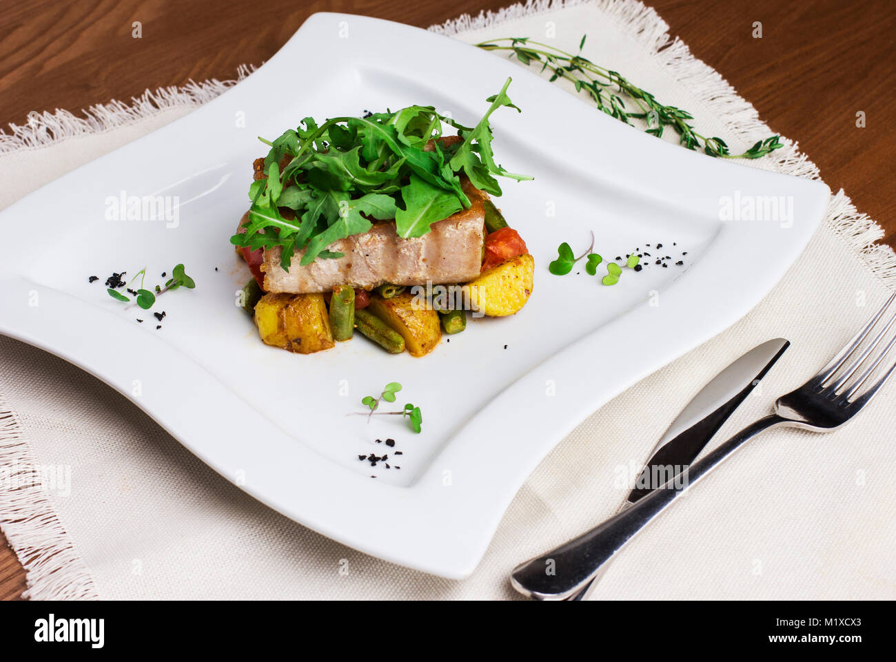 Baked fish fillets with potatoes and green beans on a square plate ...