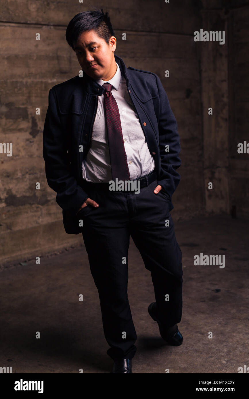 Young transgender man in formal clothing poses in a grungy urban ...
