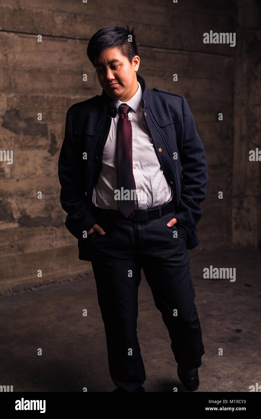 Young transgender man in formal clothing poses in a grungy urban ...