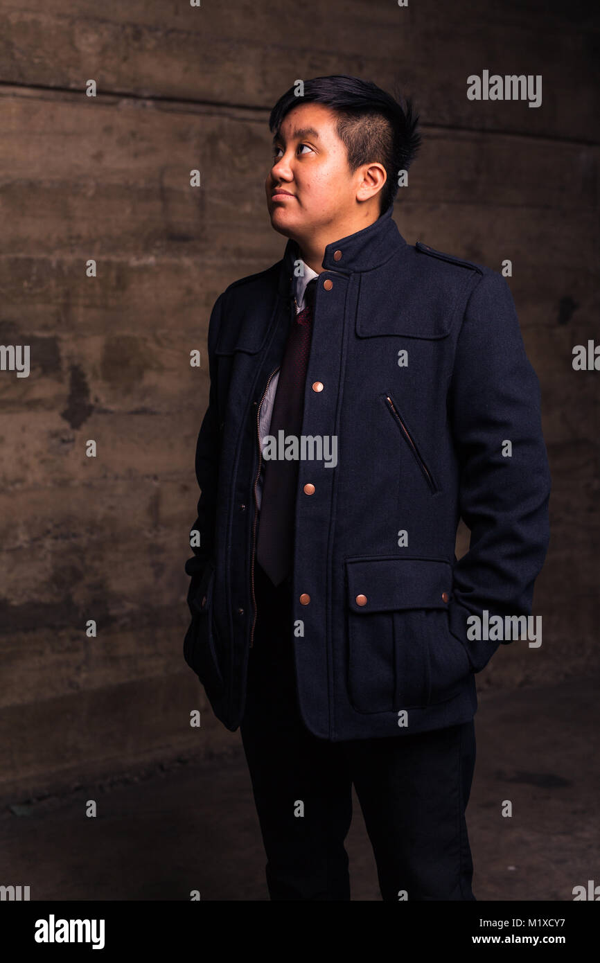 Young transgender man in formal clothing poses in a grungy urban ...