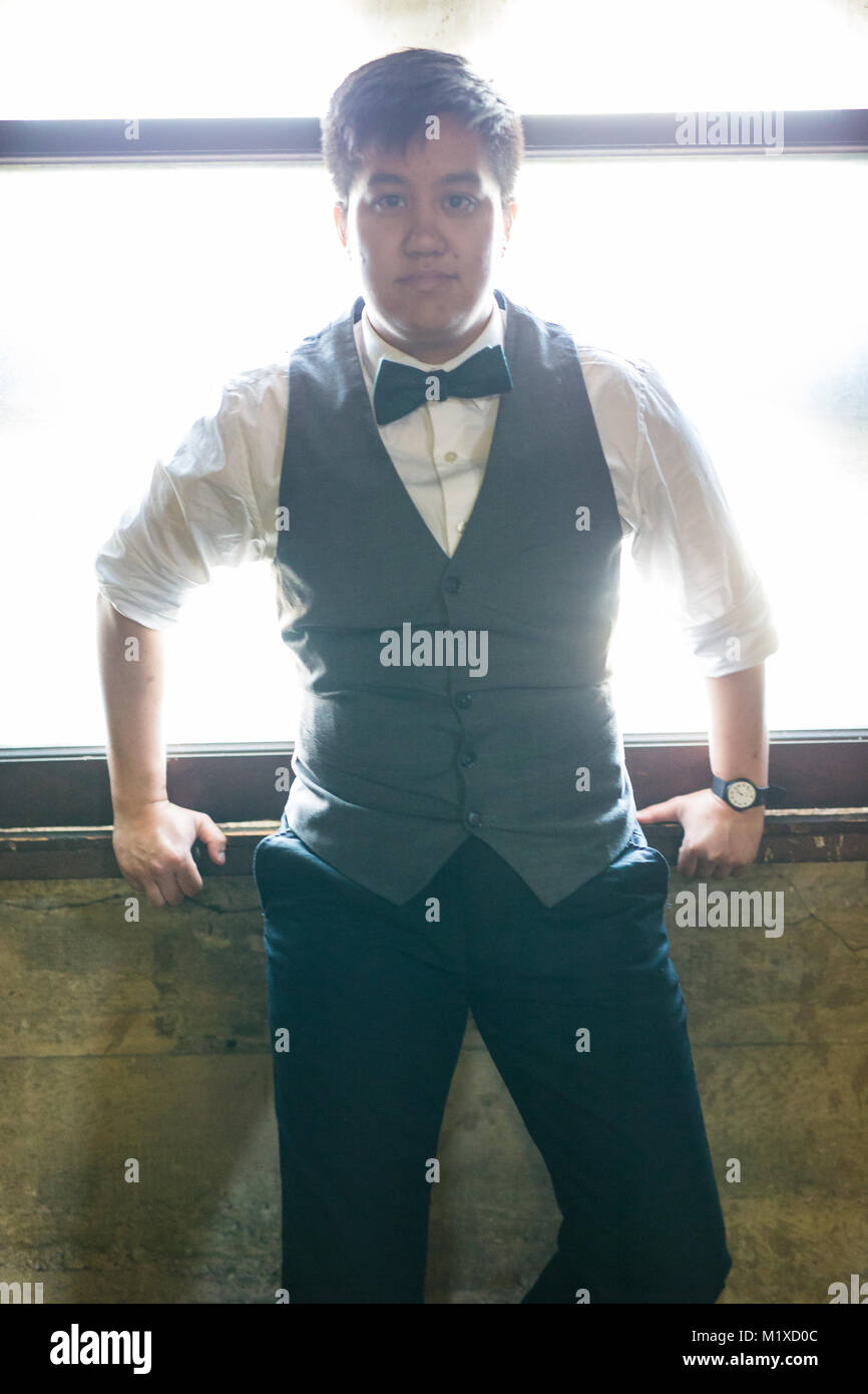 Young transgender man in formal clothing poses in a grungy urban ...