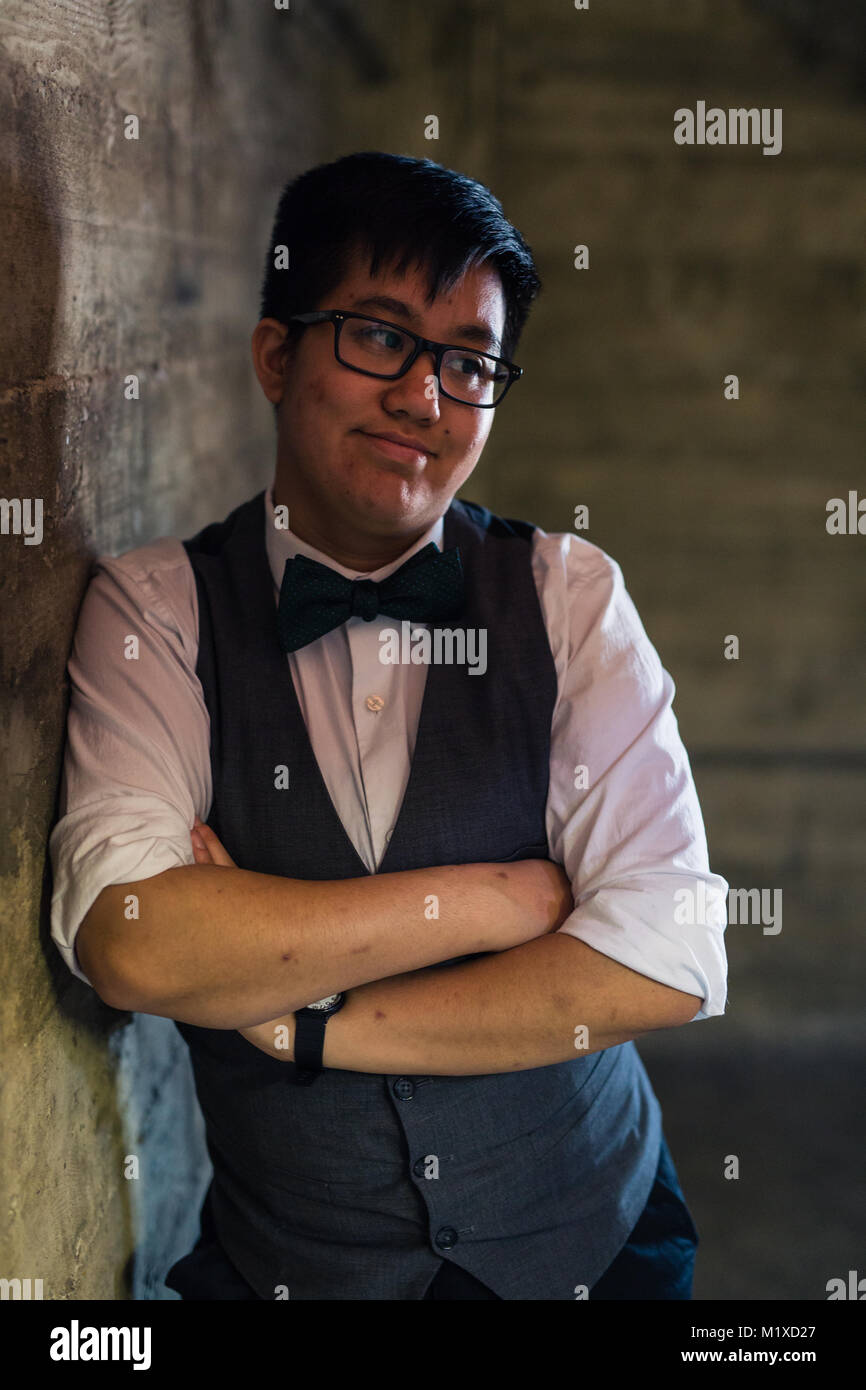 Young transgender man in formal clothing poses in a grungy urban ...
